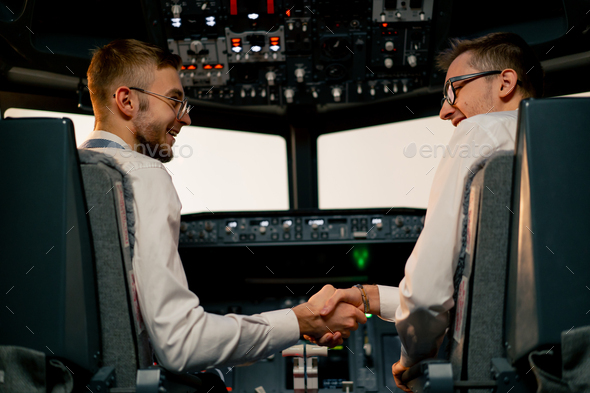 pilots in the cockpit of the plane greet each other and shake hands ...