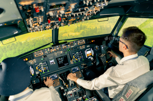 rear view of pilots in the cockpit of an airplane during flight control ...