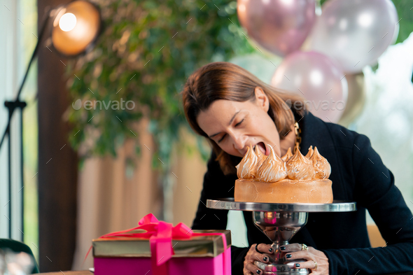 portrait of happy birthday girl biting celebration cake during party ...