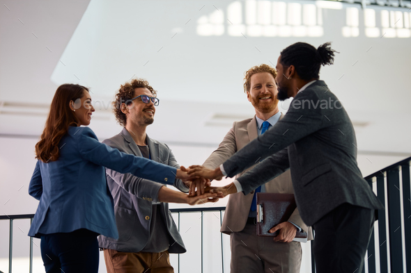Happy multiracial business team gathering their hands in unity in the ...