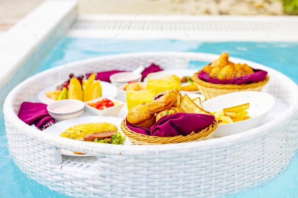 served floating tray in swimming pool with drinks and snacks on ...