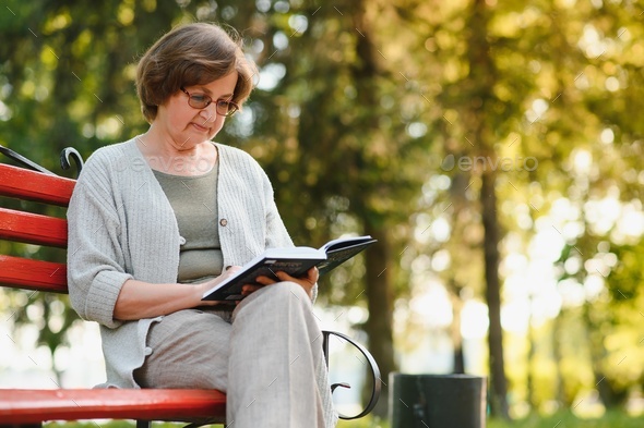 Retired woman reading a book on the bench Stock Photo by sedrik2007