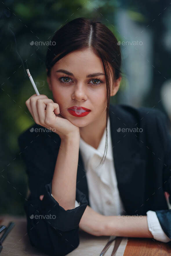 Stylish fashion woman portrait sitting in a cafe at a table and smoking ...