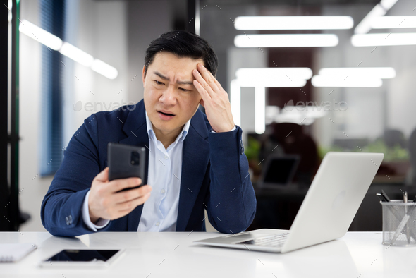 Sad disappointed asian man at workplace, dissatisfied employee in ...