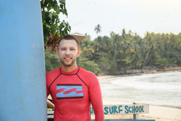 Surfer with special natural sunblock zink on his face holding his ...