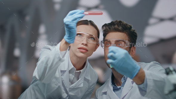 Two researchers examining vaccine sample in biotechnical laboratory ...