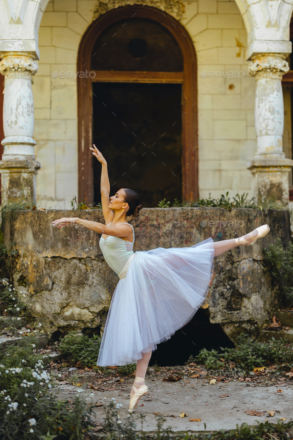Prima ballerina is making beautiful figure in front of a rustic ...
