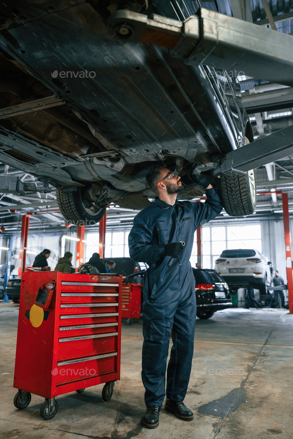 Fixing broken vehicle. Car repairman is in the garage with automobile ...