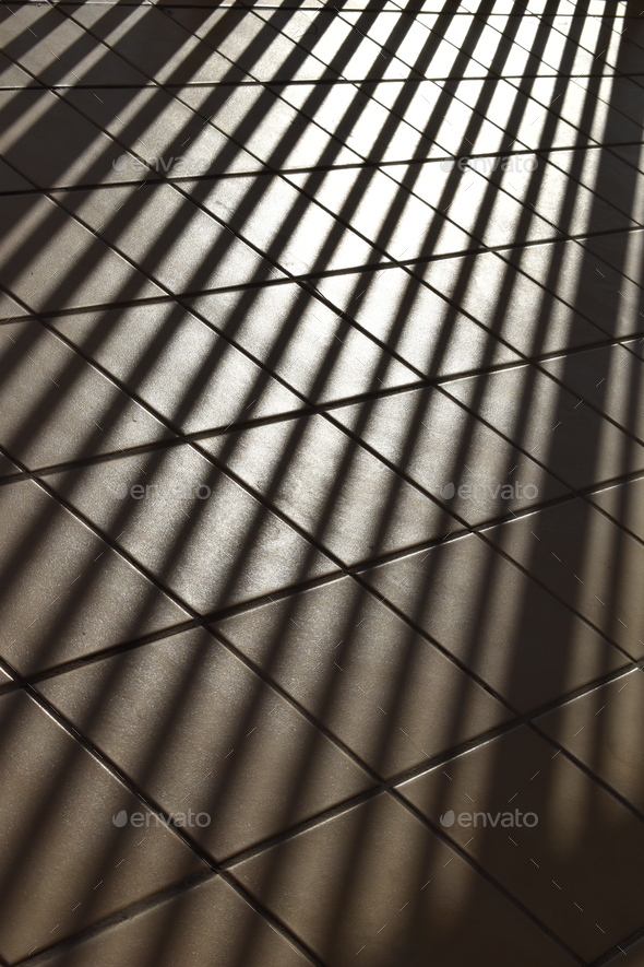 Sunlight illuminating tiled floor creating grid shadows Stock Photo by wirestock