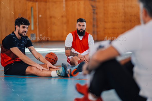 Basketball players sitting and listening their coach on training. Stock ...