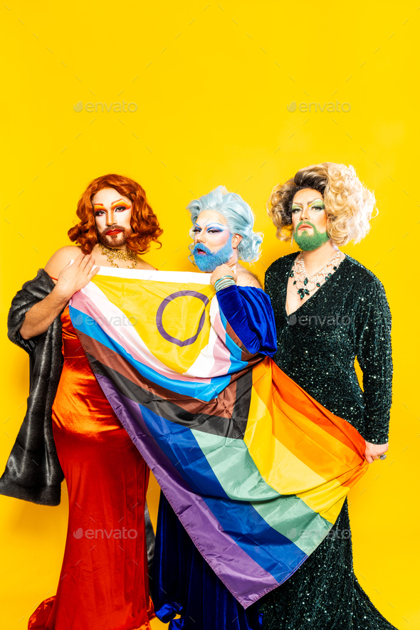 Group of drag queens looking at camera and holding rainbow flag Stock ...