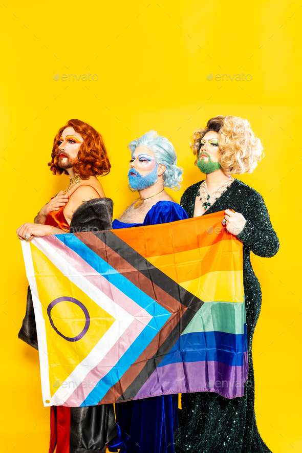 Drag queens standing together with Pride flag Stock Photo by galdricp