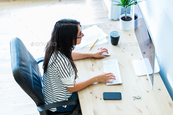 Productive young woman working on computer at home office Stock Photo ...