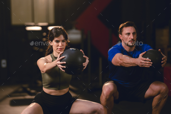 Personal trainer coach helping young woman exercising in the sport gym ...
