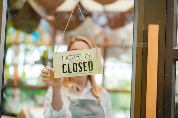 Woman staff turning close sign board on glass door in coffee shop and ...