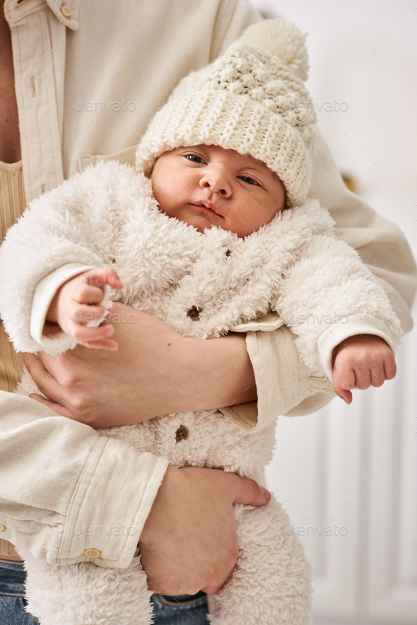adorable newborn baby in warm comfortable attire in hands of his loving ...