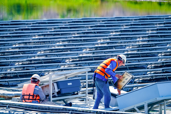Local worker working at floating solar panels platform on the water of ...