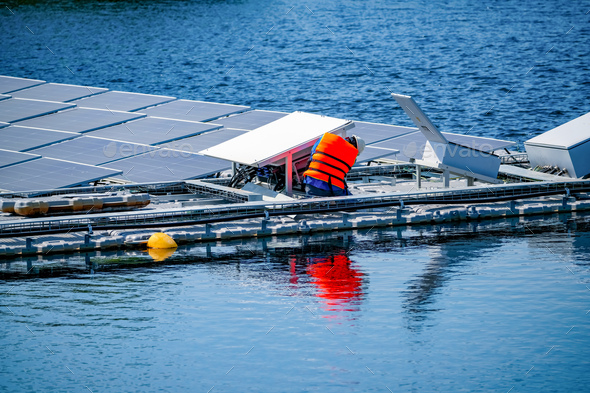 Local worker working at floating solar panels platform on the water of ...