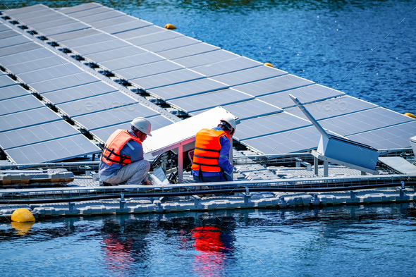 Local worker working at floating solar panels platform on the water of ...