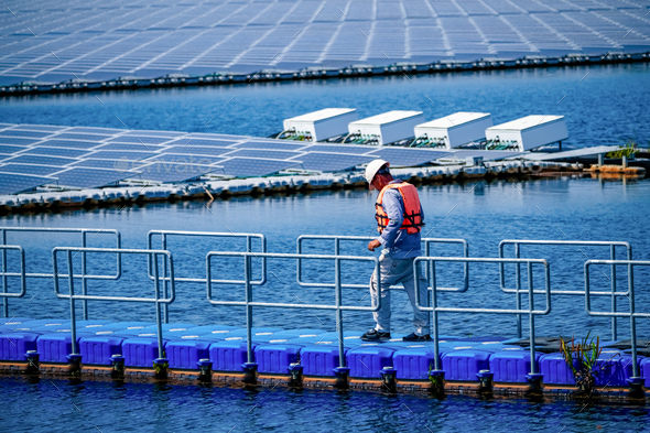 Local worker working at floating solar panels platform on the water of ...