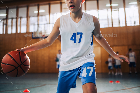 Cropped picture of young athlete dribbling a basketball on court. Stock ...
