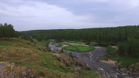 Aerial view of a high rock on the river bank. Rapids on the river ...