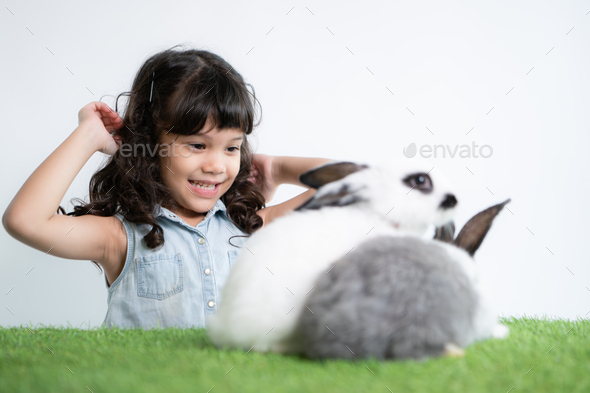 Smiling little girl and with their beloved fluffy rabbit, showcasing ...