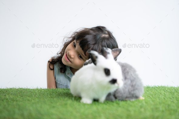 Smiling little girl and with their beloved fluffy rabbit, showcasing ...