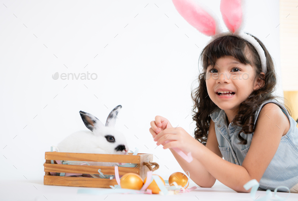 Smiling little girl and with their beloved fluffy rabbit, showcasing ...