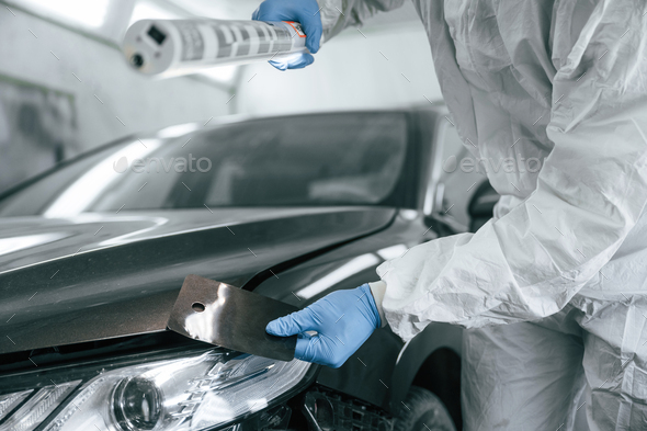 Choosing right color. Garage worker is holding lighting and checking ...
