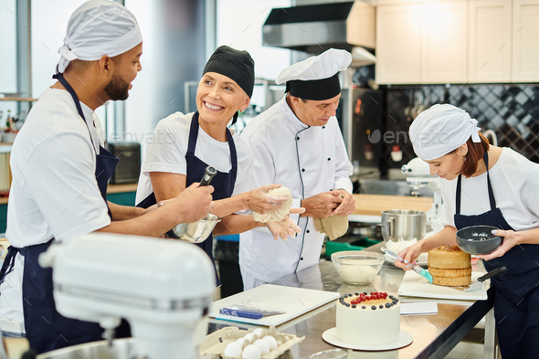 jolly chef smiling at her african american colleague with their friend ...