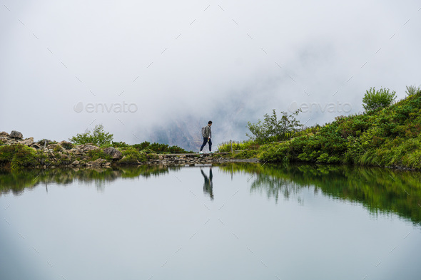 Man happy traveler hiking on the walk way with beautiful mountains view ...