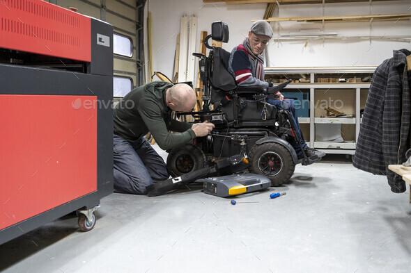 Mechanic working on mans prototype wheelchair Stock Photo by Image-Source