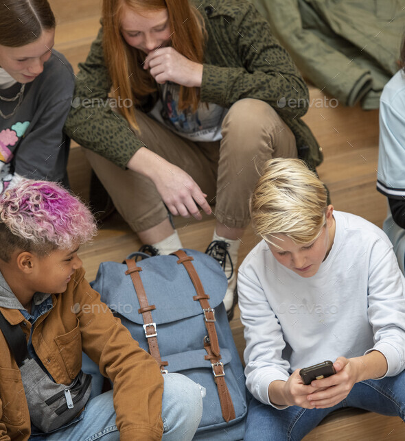Group of young teenagers bonding at school, while looking at their ...
