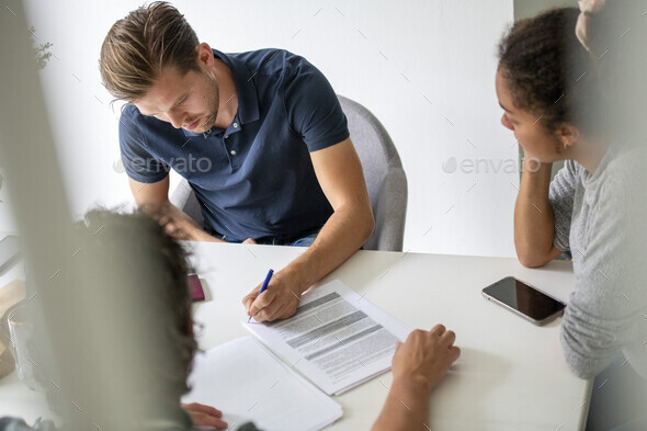 Focused team members review documents at a white table. Stock Photo by ...