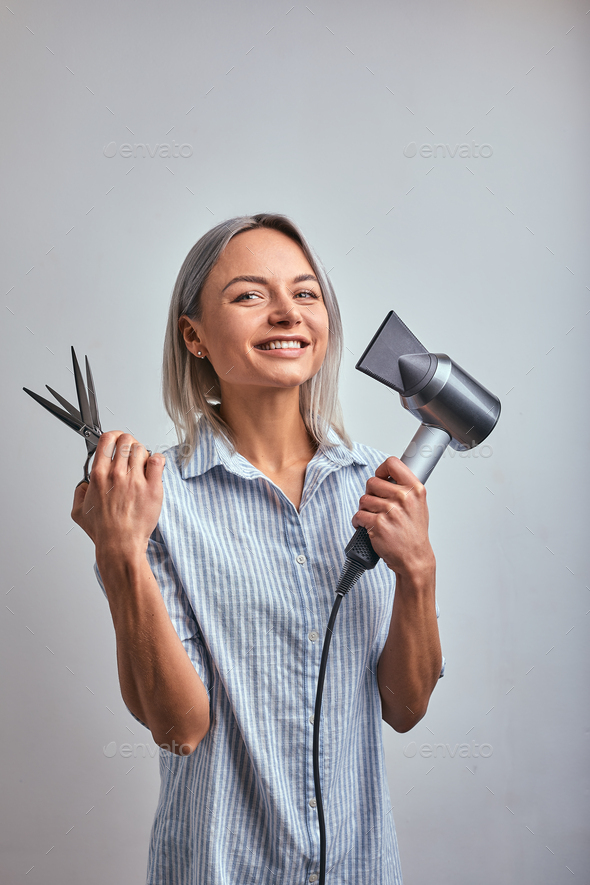 Attractive woman blonde hairdresser with professional tool posing on ...