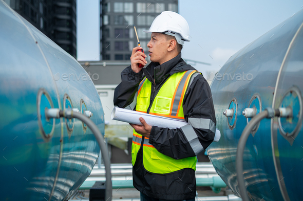 Engineer inspects water heater pump system and hot water tank on ...