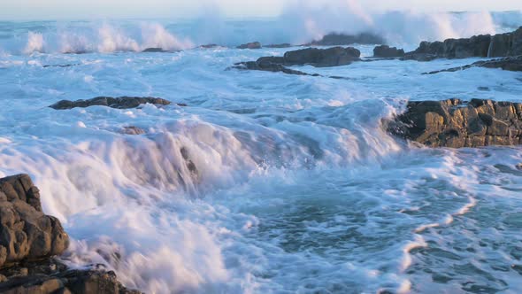 Waves pushing flowing seawater over rocks into another pool, close-up ...