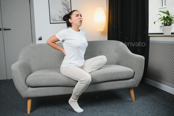Sad young woman touching back feeling backache morning discomfort low ...