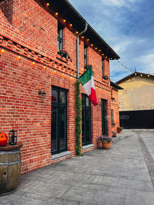Italian flag on rick row house. Facade of brick building with Italian ...
