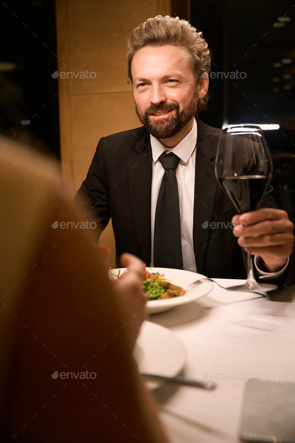 Man makes a toast at dinner in a restaurant Stock Photo by Iakobchuk