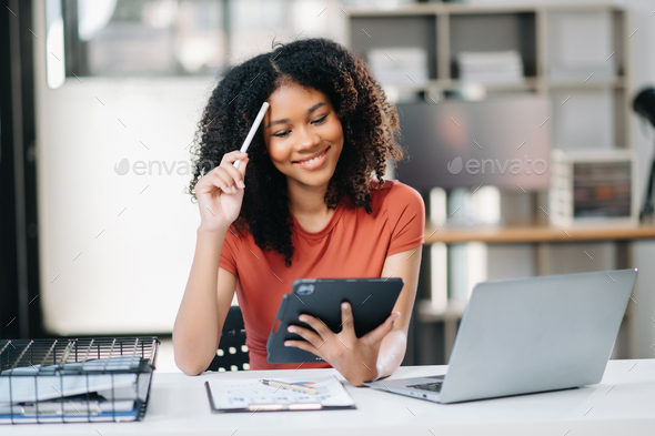 Confident woman with a smile standing holding notepad and tablet at the ...
