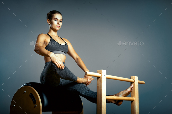 Beautiful woman doing pilates exercise, training on barrels. Barrel ...