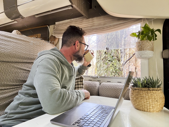 One adult man using a laptop inside a camper van in vanlife remote ...