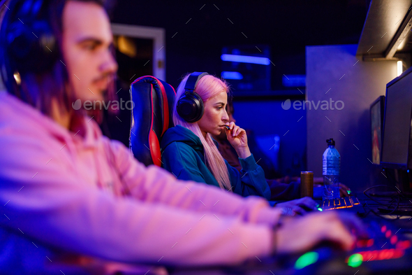 Woman pro gamer wearing headphones and talking with her team on a ...