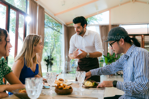 Waitress serving food to group of diverse customer in restaurant ...