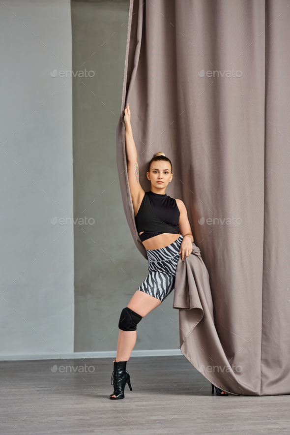 expressive woman in dance clothing and high heels gracefully poses near ...