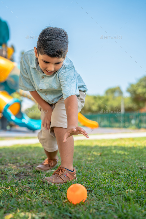 School latin boy grabbing a ball in a park Stock Photo by GSR-PhotoStudio