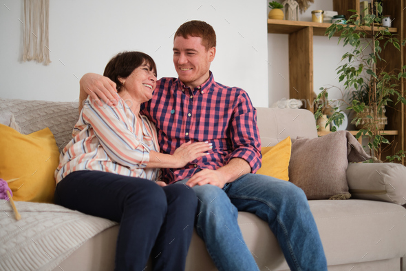 caring son affectionately cuddles his happy, elderly, retired mother ...