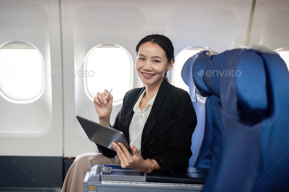 Smiling happy business woman asian flying and working in an airplane in ...